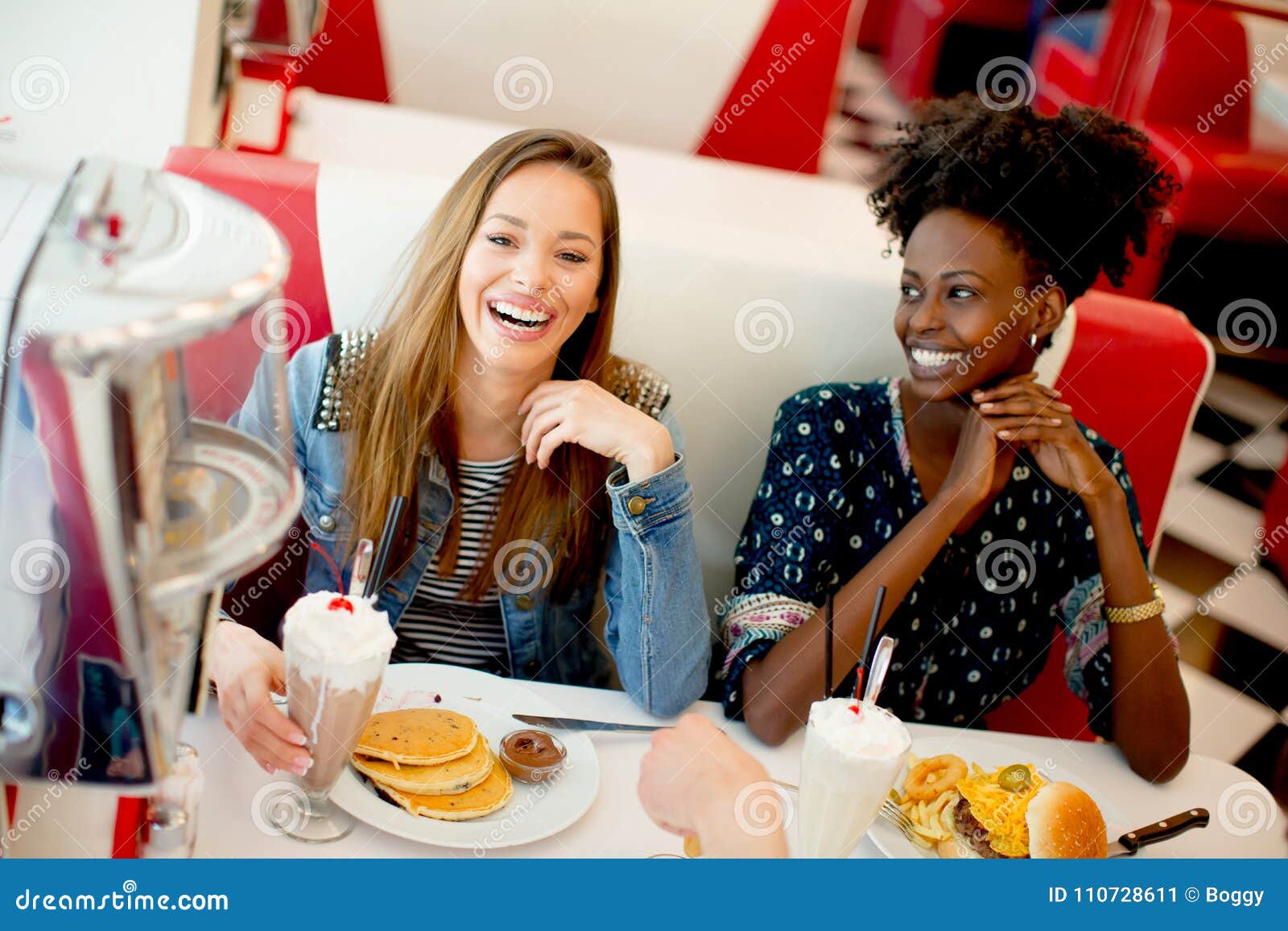 Multiracial Female Friends Eating Fast Food At A Table In The Di Stock