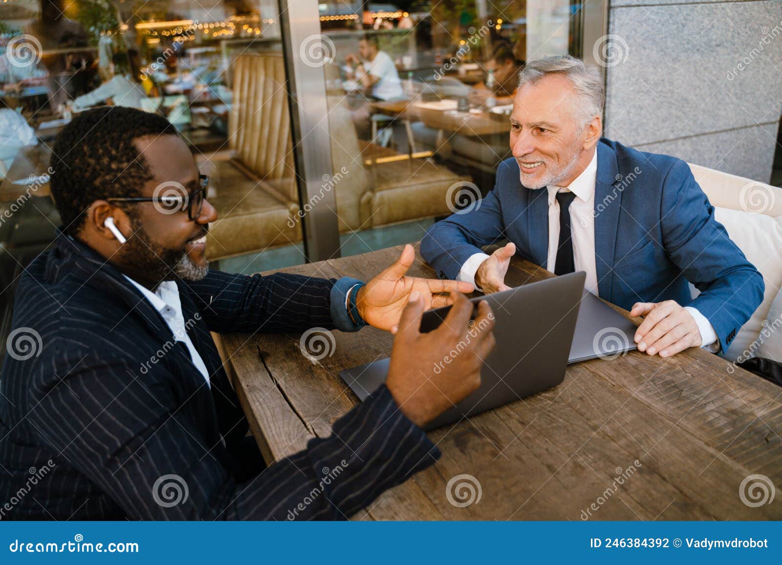 Multiracial Men Talking while Working with Laptops in Cafe Stock Photo ...