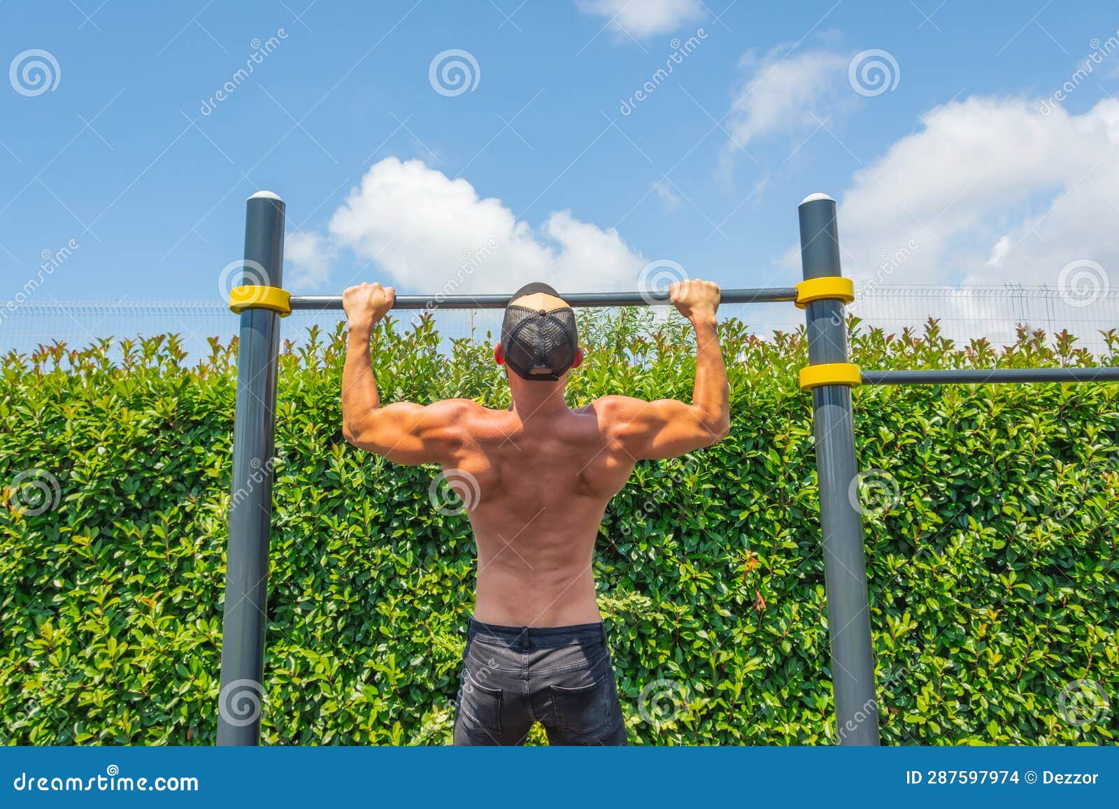 Muscular Caucasian Man in a Cap Doing Pull-ups on the Horizontal Bar in ...