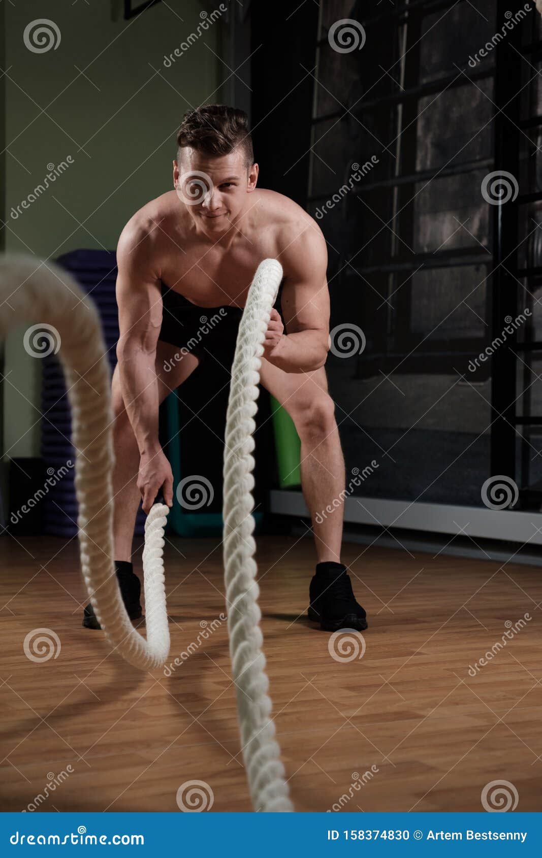 Muscular Man with Battle Rope Doing Exercise in Functional Training Gym ...