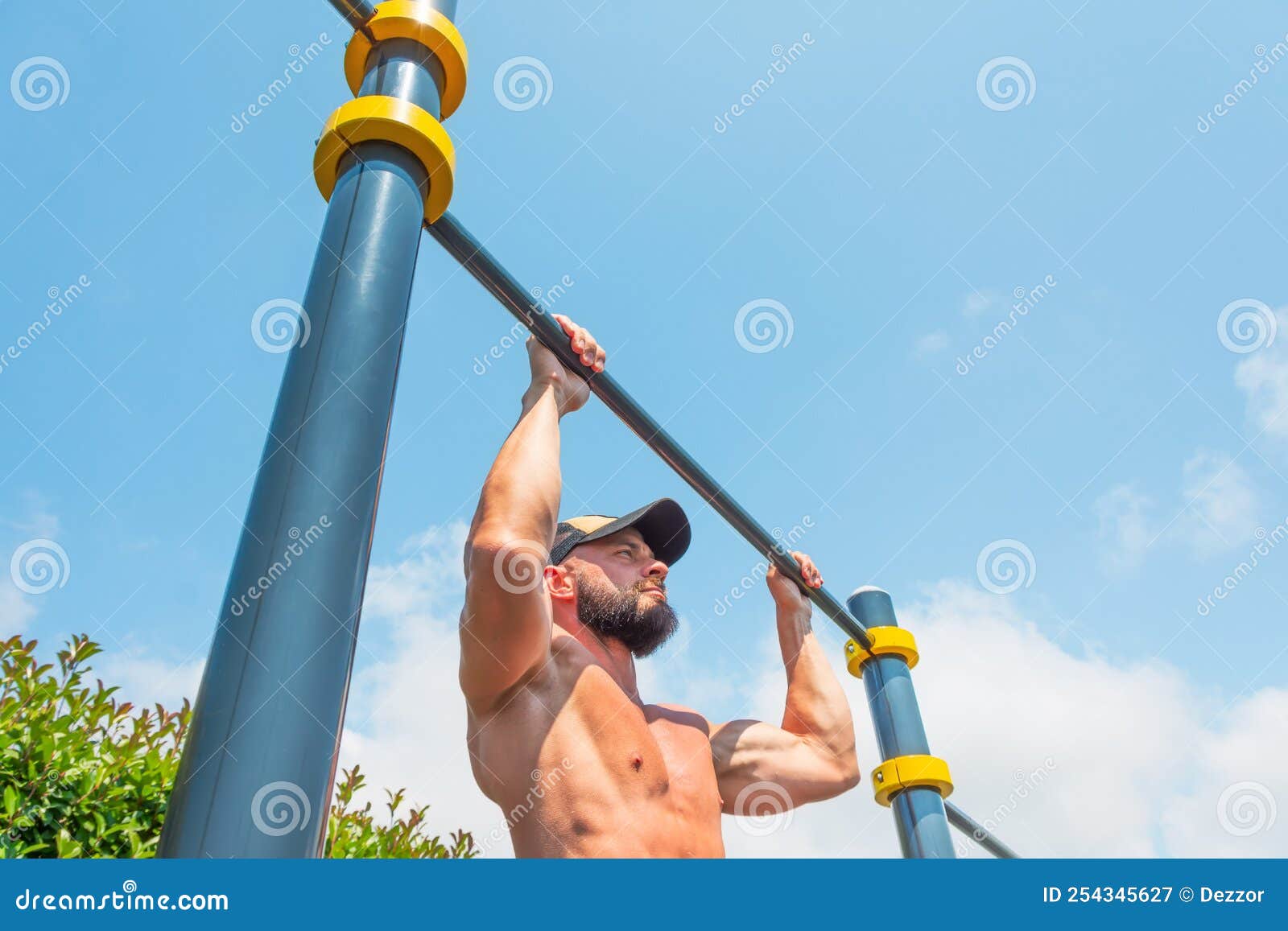 Muscular Man in a Cap Doing Pull-ups on the Horizontal Bar in the Park Outdoors Stock Image ...