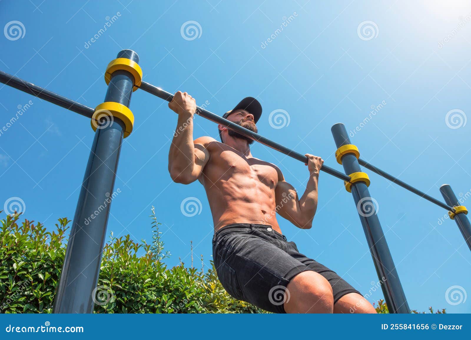 Muscular Man In A Cap Doing Reverse Pull Up On The Horizontal Bar In