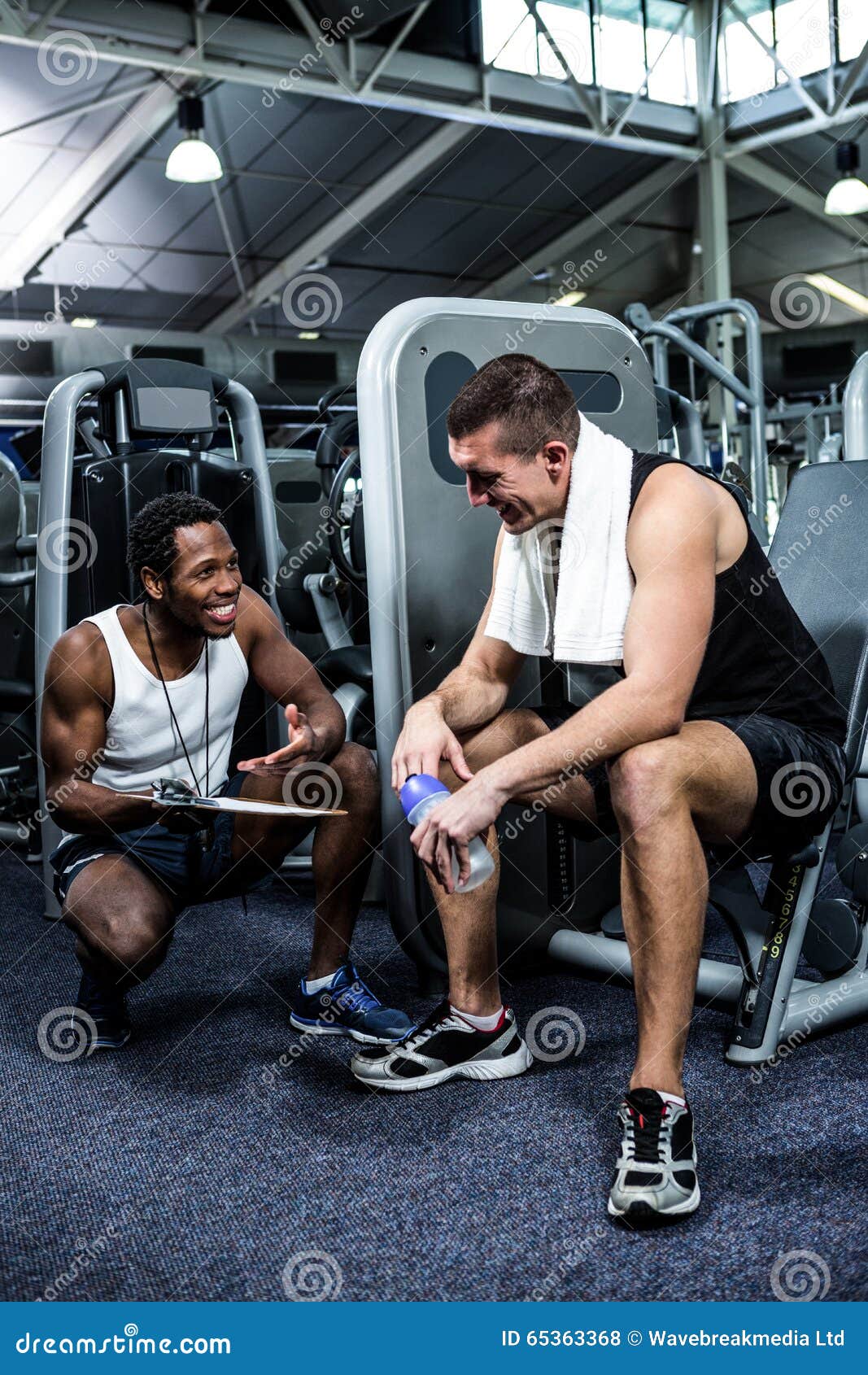 Muscular Man Discussing Performance with Trainer Stock Photo - Image of ...