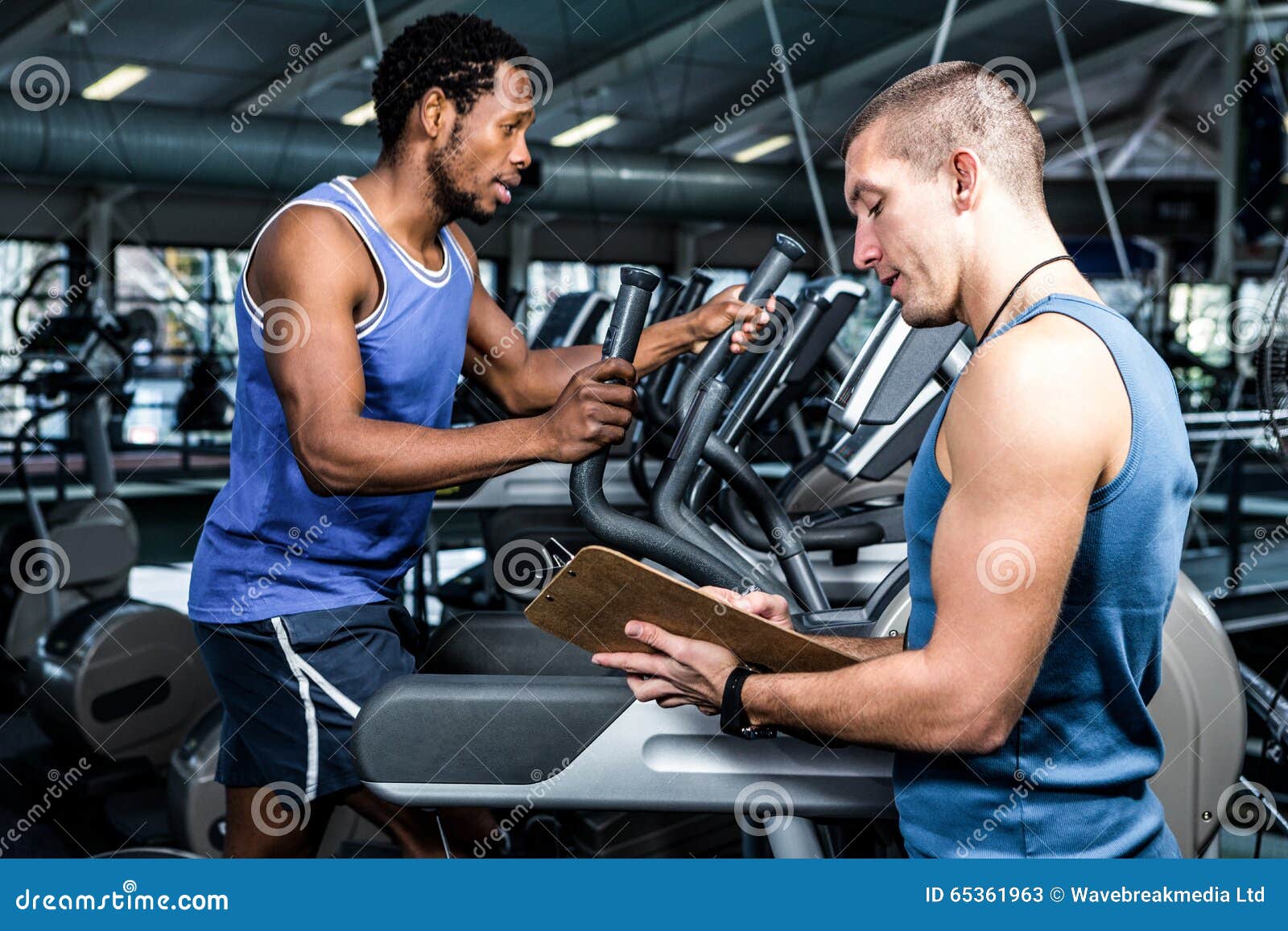 Muscular Man Using Elliptical Machine with Trainer Stock Image - Image ...