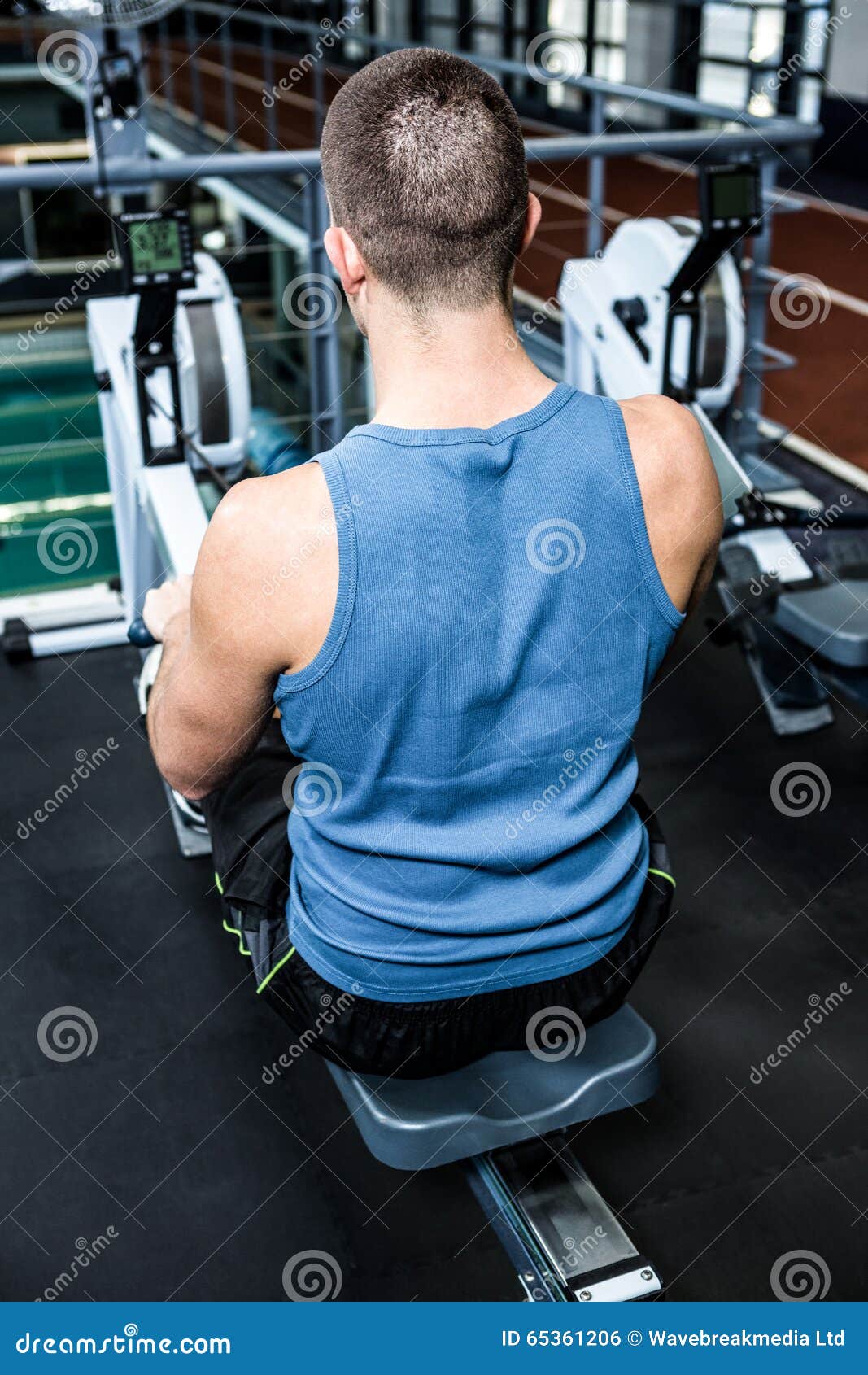 Muscular Man Using Rowing Machine Stock Photo - Image of exercising ...