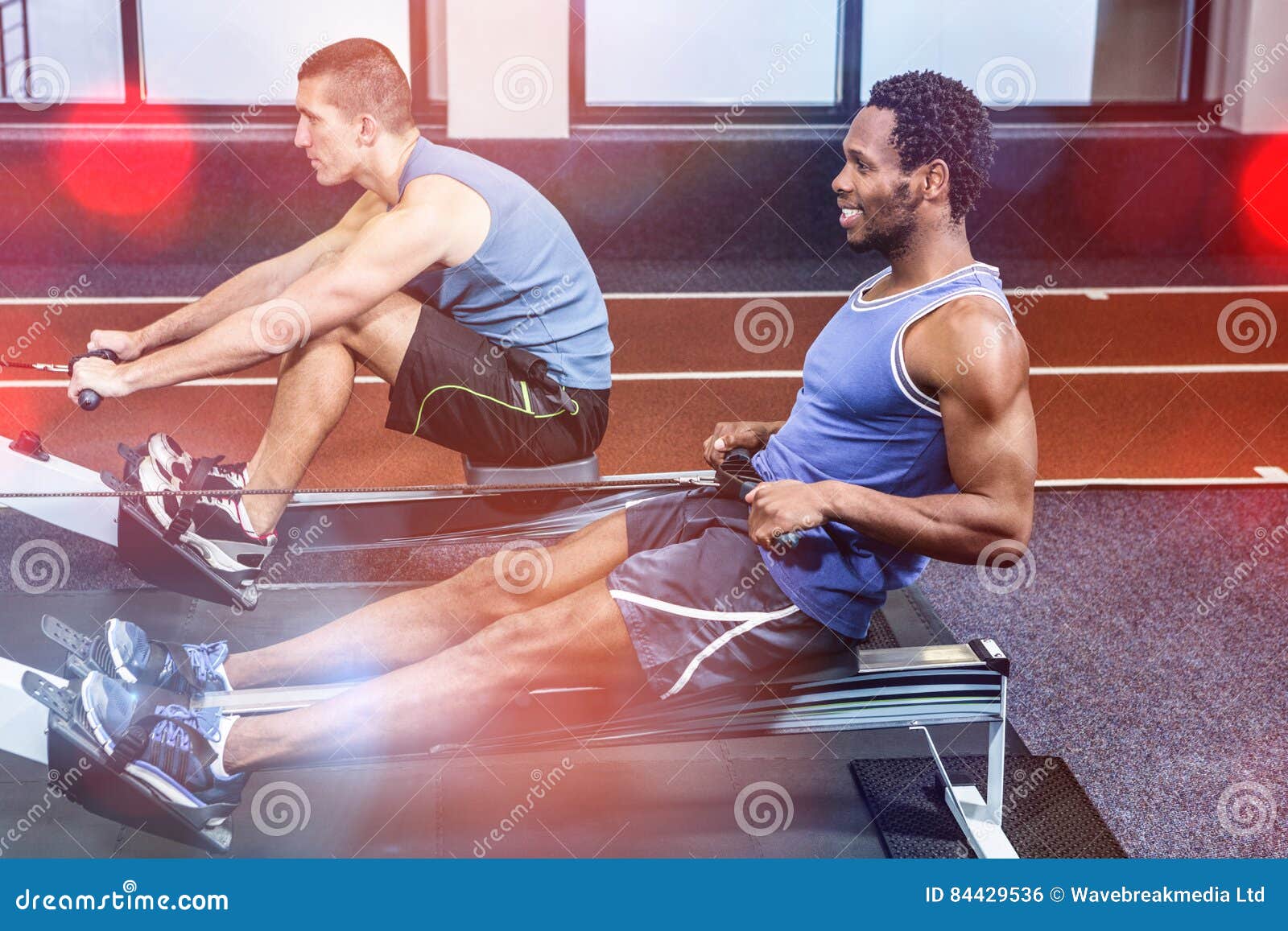 Muscular Men Using Rowing Machine Stock Photo - Image of focused, male ...
