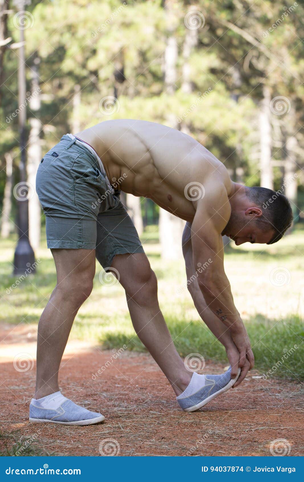 The Muscular Young Man Doing Stretching Exercises in the Park Stock ...