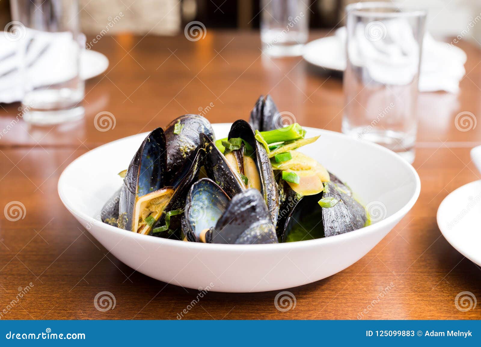 Mussels in Shells in a White Bowl with a Green Sauce on a Dining Table ...
