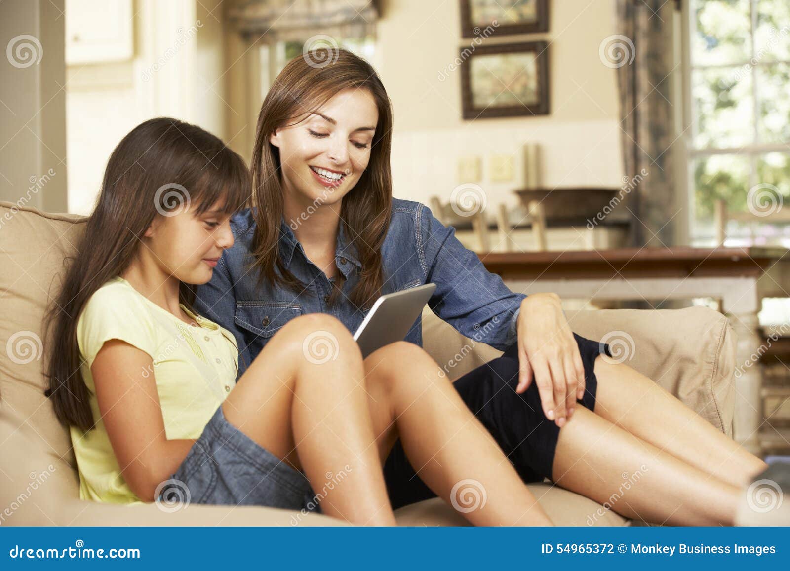 Mutter Und Tochter, Die Auf Sofa at Home Using Tablet-Computer Sitzen ...