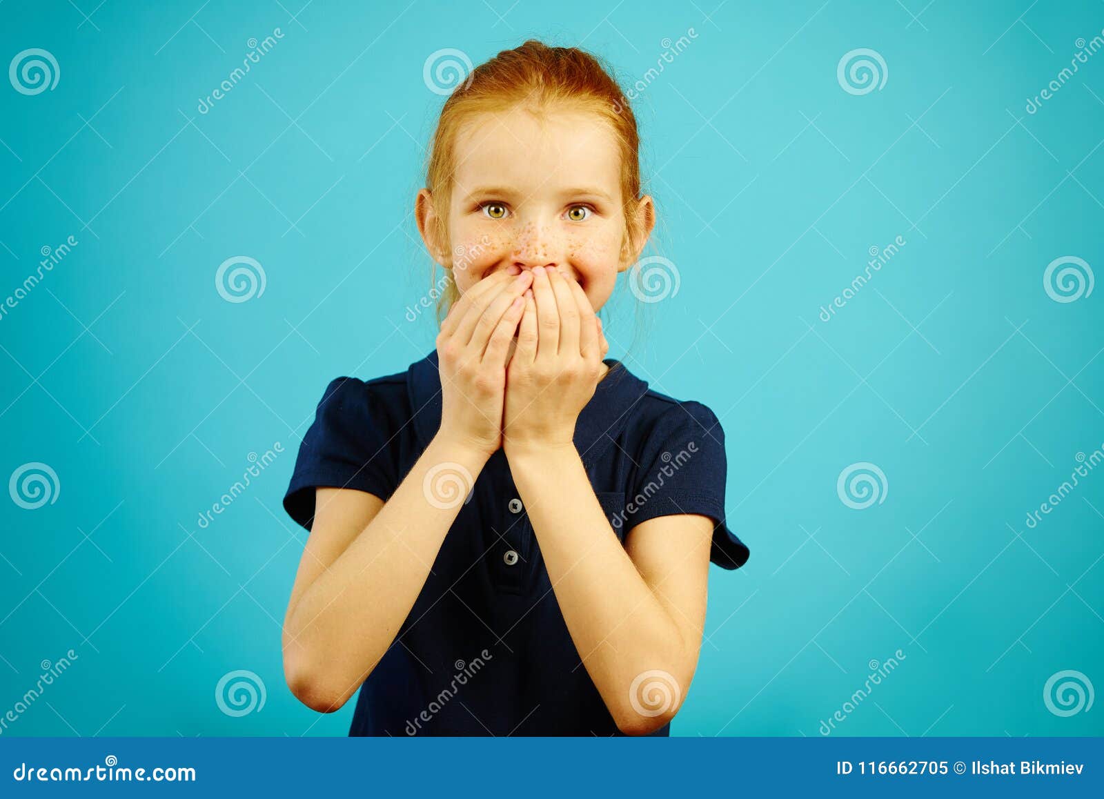 Naughty Girl With Cheerful Expression Closes Her Mouth With Hands Has