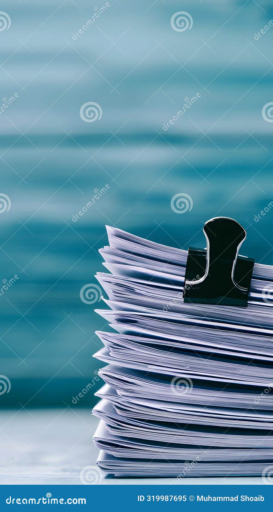 Neat Stack of Papers with Black Clip on Blue Background, Exuding ...