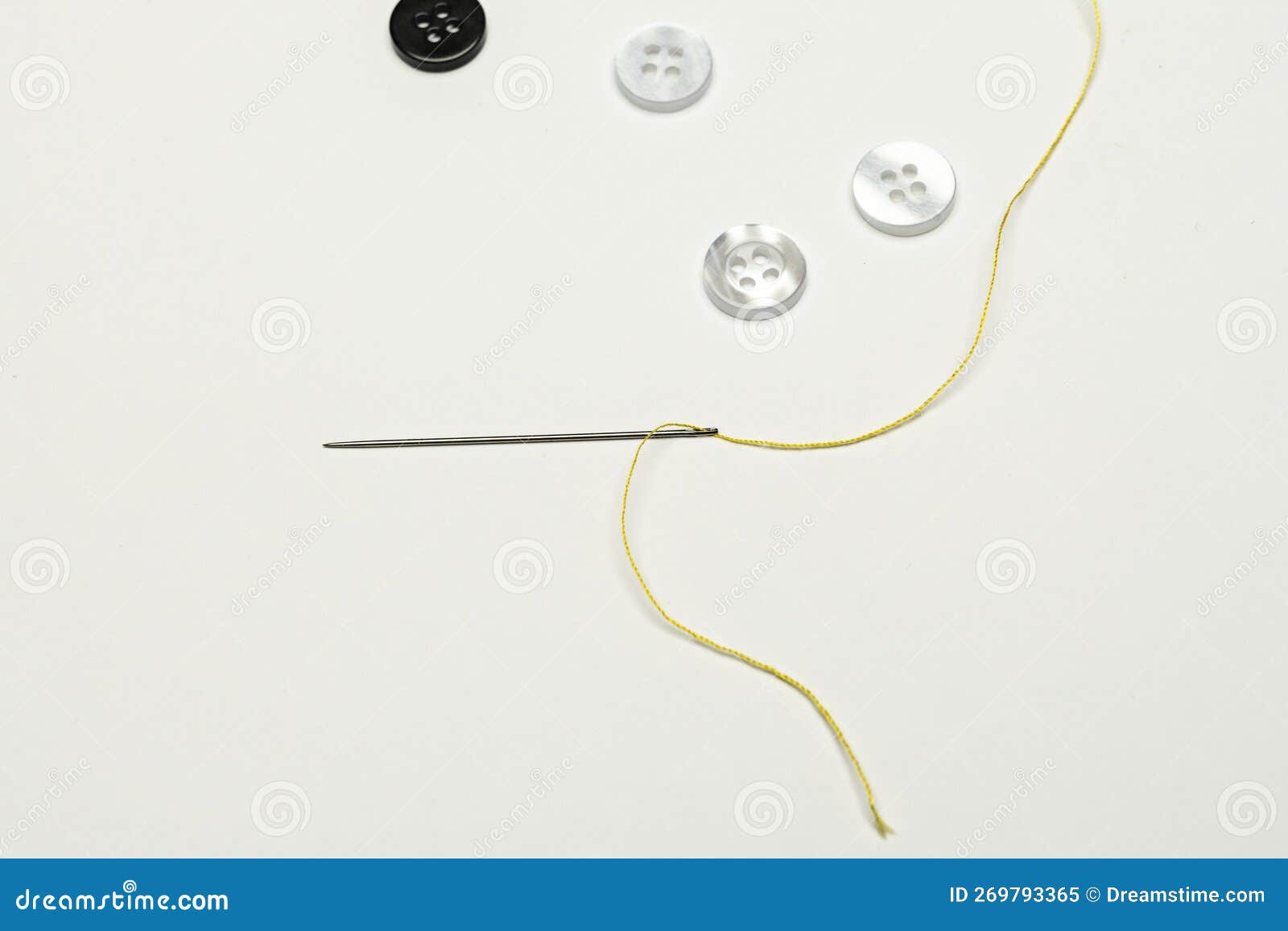 Needle with Yellow Thread Threaded Together with Some White Buttons and ...