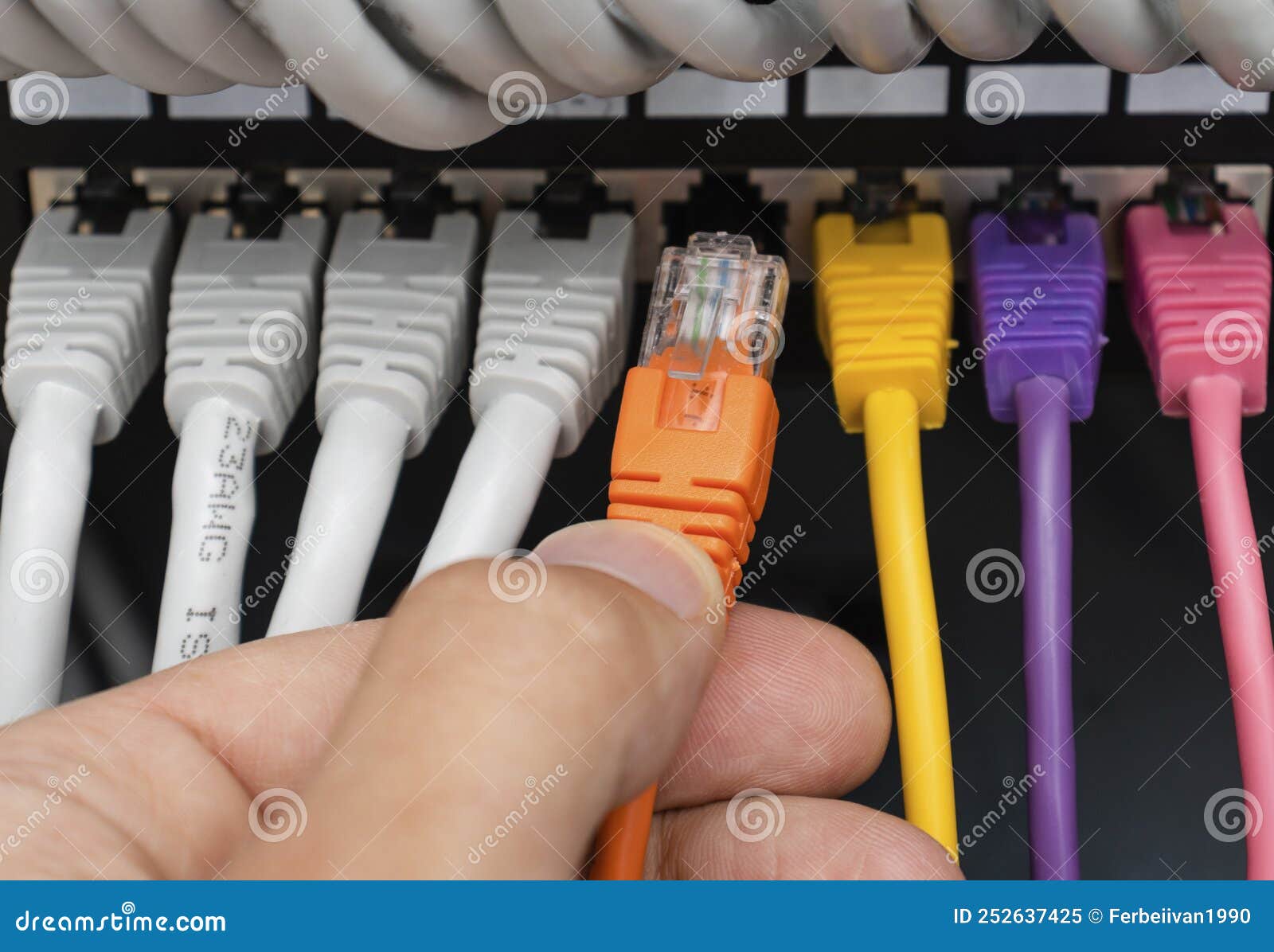 Network Engineer Connecting an Orange Ethernet Cable into Patch Panel ...