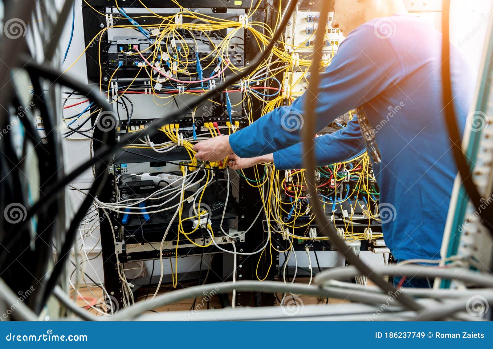Network Engineer Working in Server Room. Connecting Network Cables To ...