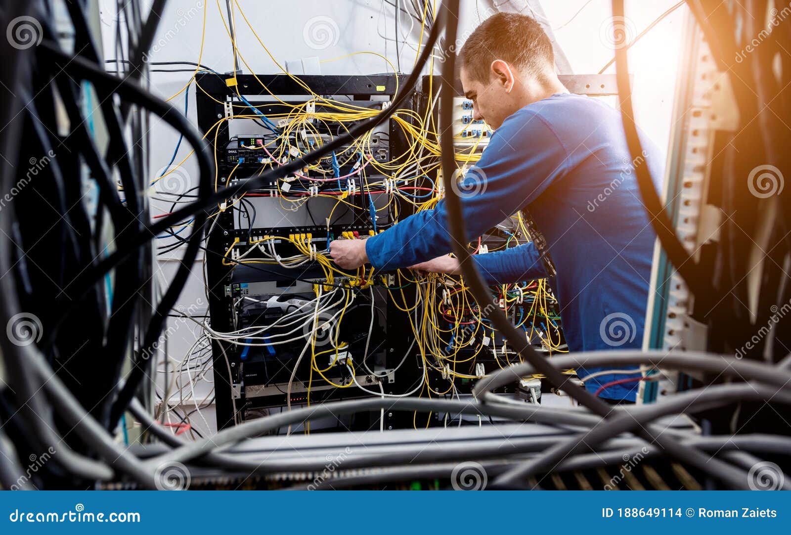 Network Engineer Working in Server Room. Connecting Network Cables To ...