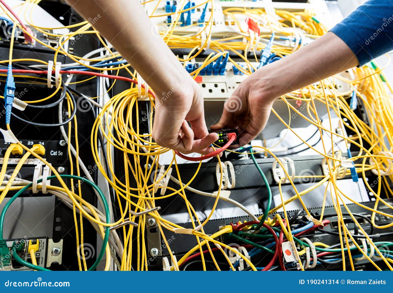 Network Engineer Working in Server Room. Connecting Network Cables To ...