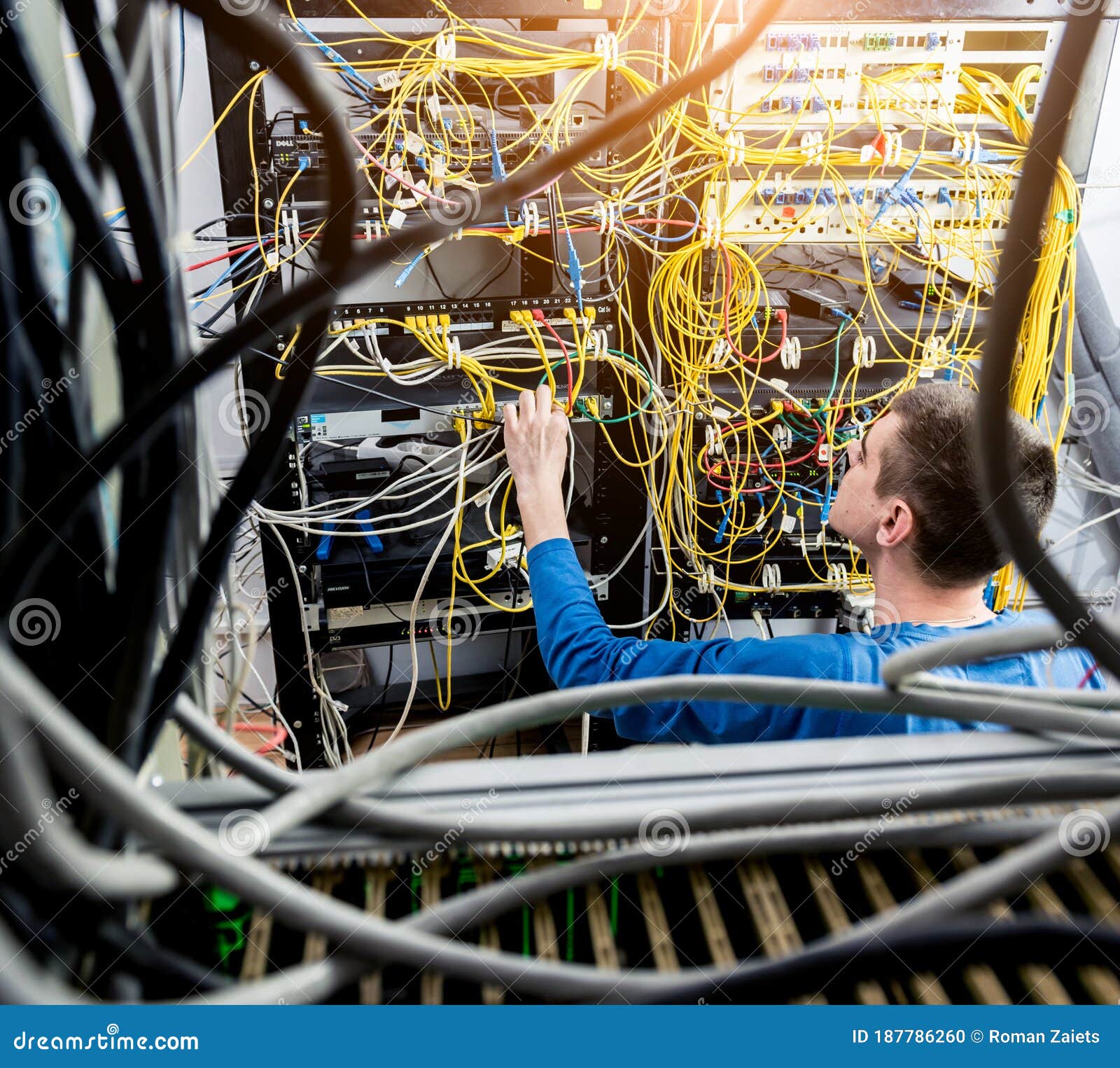 Network Engineer Working in Server Room. Connecting Network Cables To ...