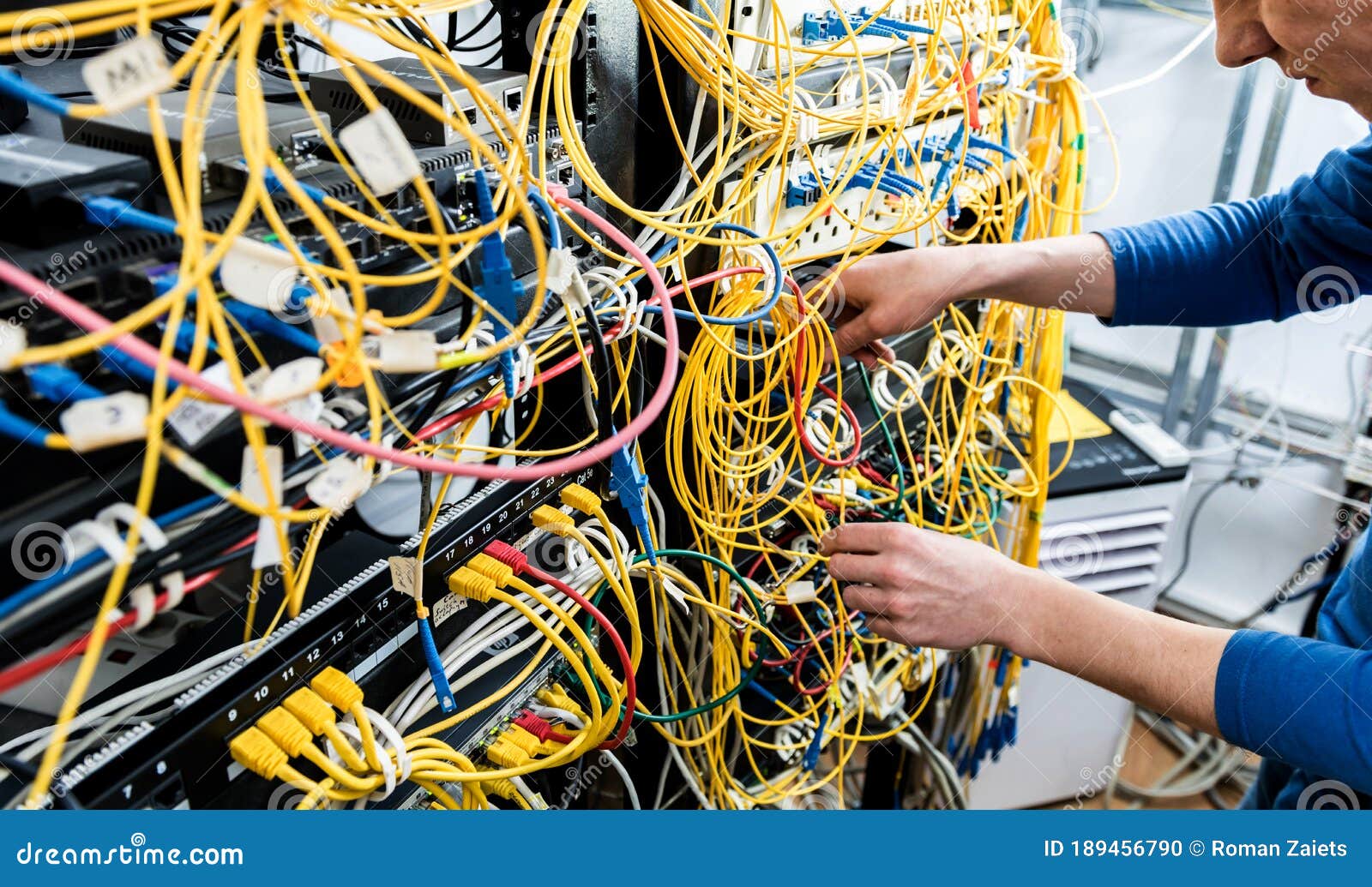 Network Engineer Working in Server Room. Connecting Network Cables To ...