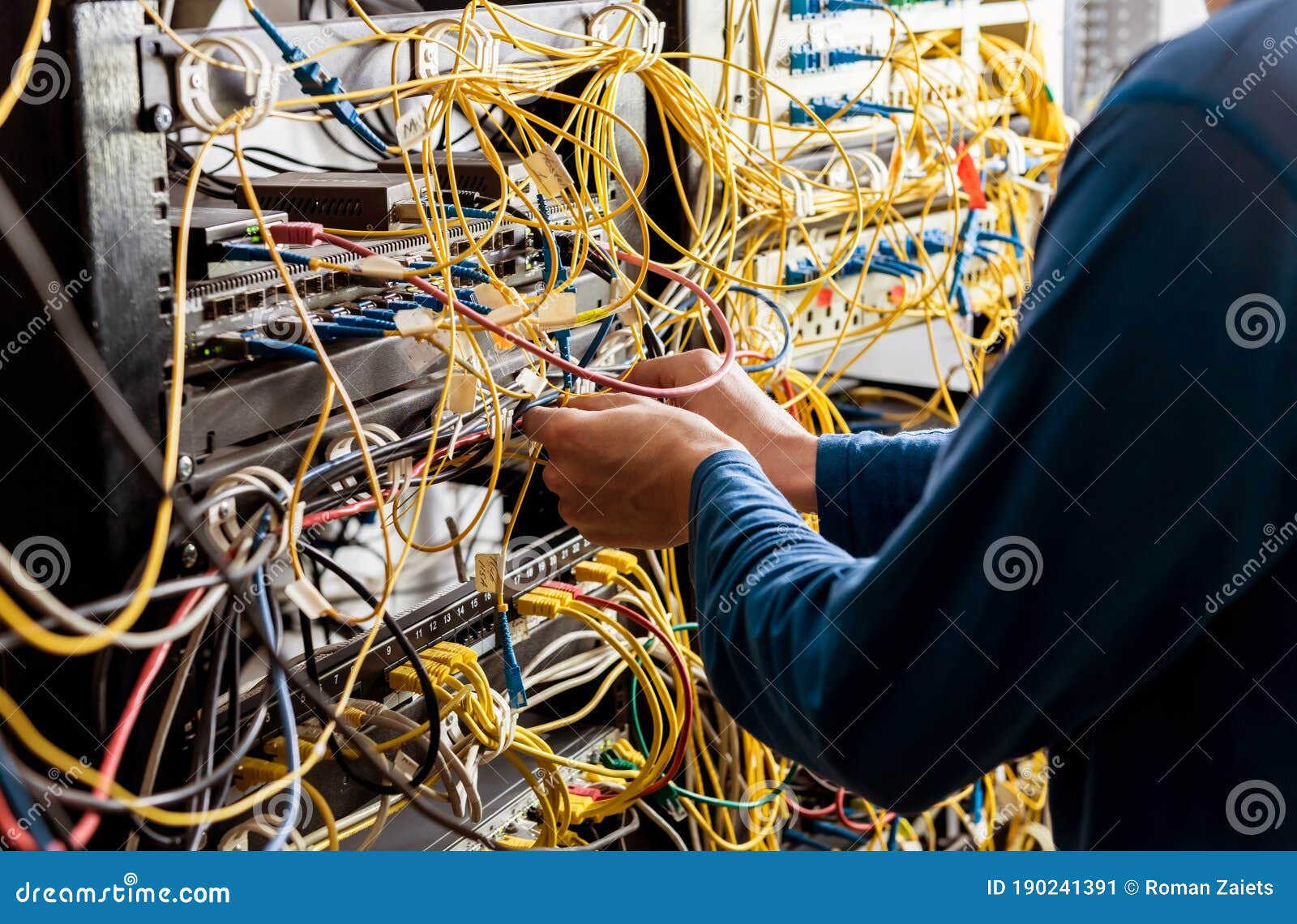 Network Engineer Working in Server Room. Connecting Network Cables To ...