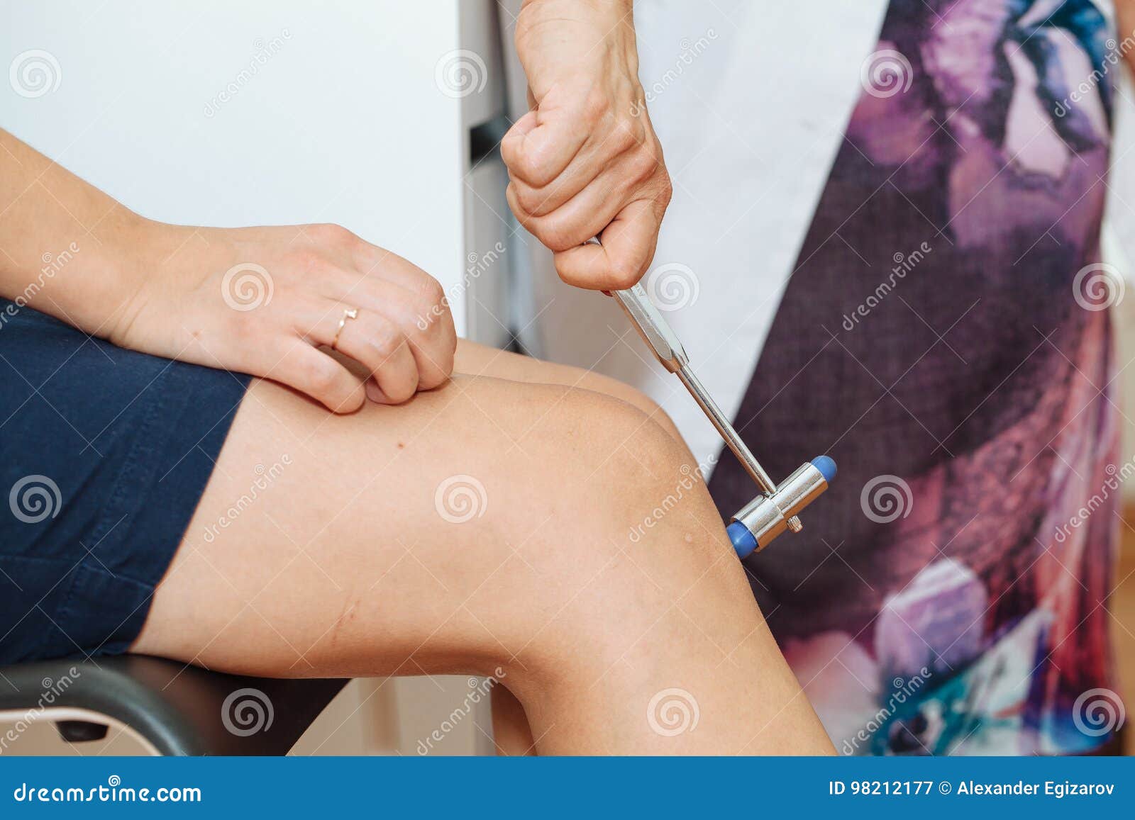 The Neurologist Testing Knee Reflex On A Female Patient Using A Hammer ...