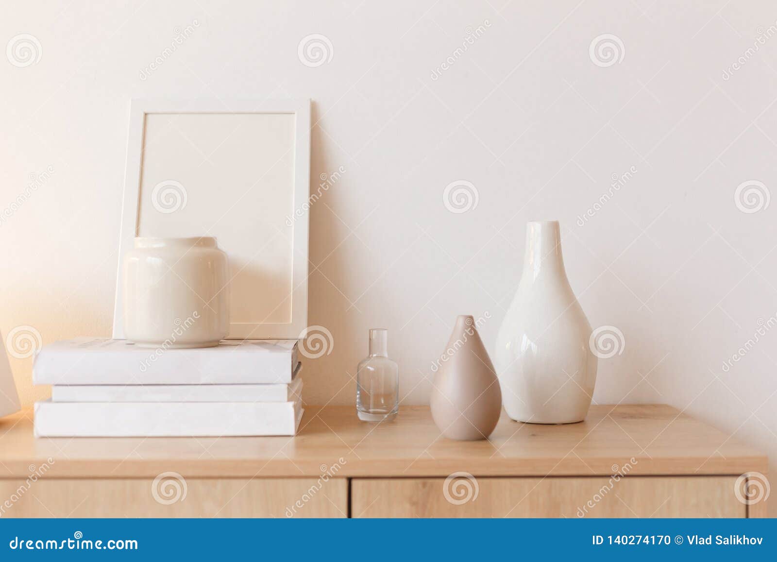 Neutral Colored Vases, Photo Frame and Stack of Books on Bureau Shelf ...