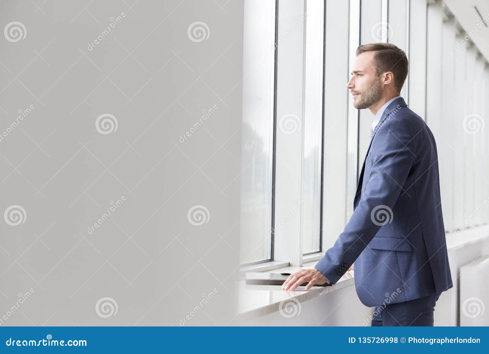 Thoughtful Handsome Young Businessman Looking through Window in New ...