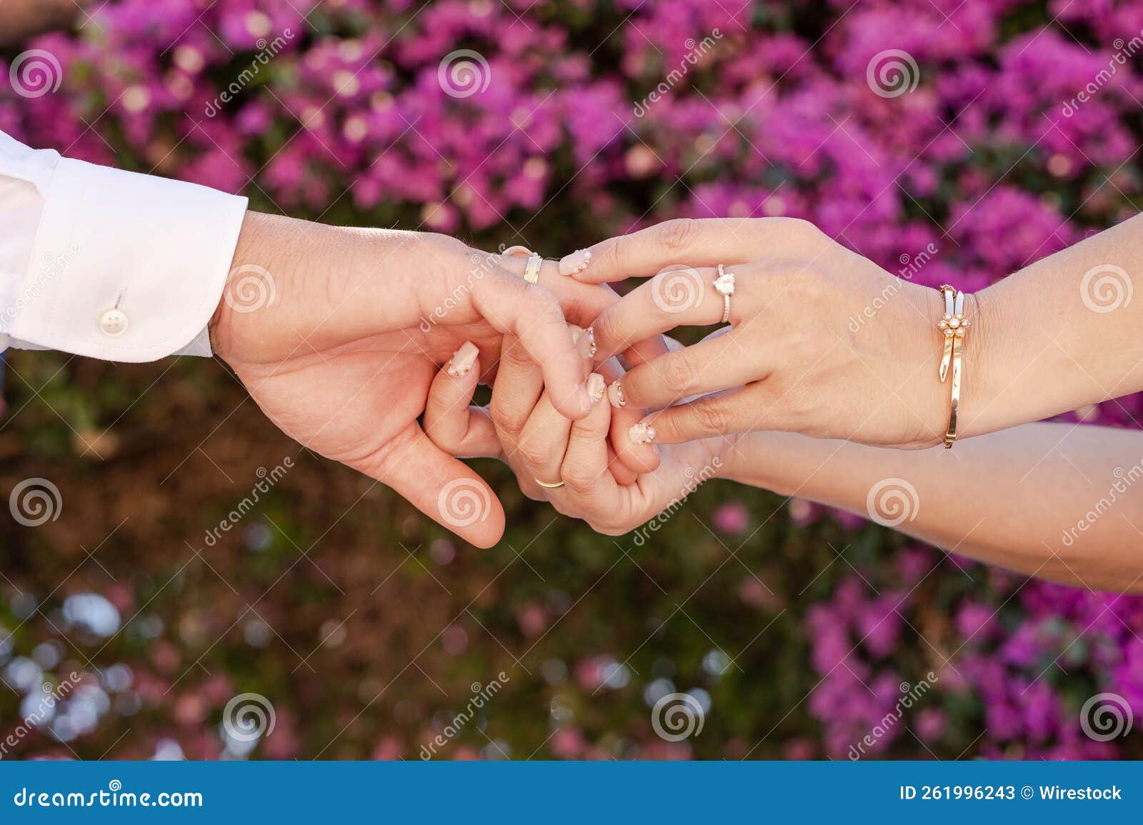 Newly Married Couple Holding Hands And Wedding Rings In The Foreground
