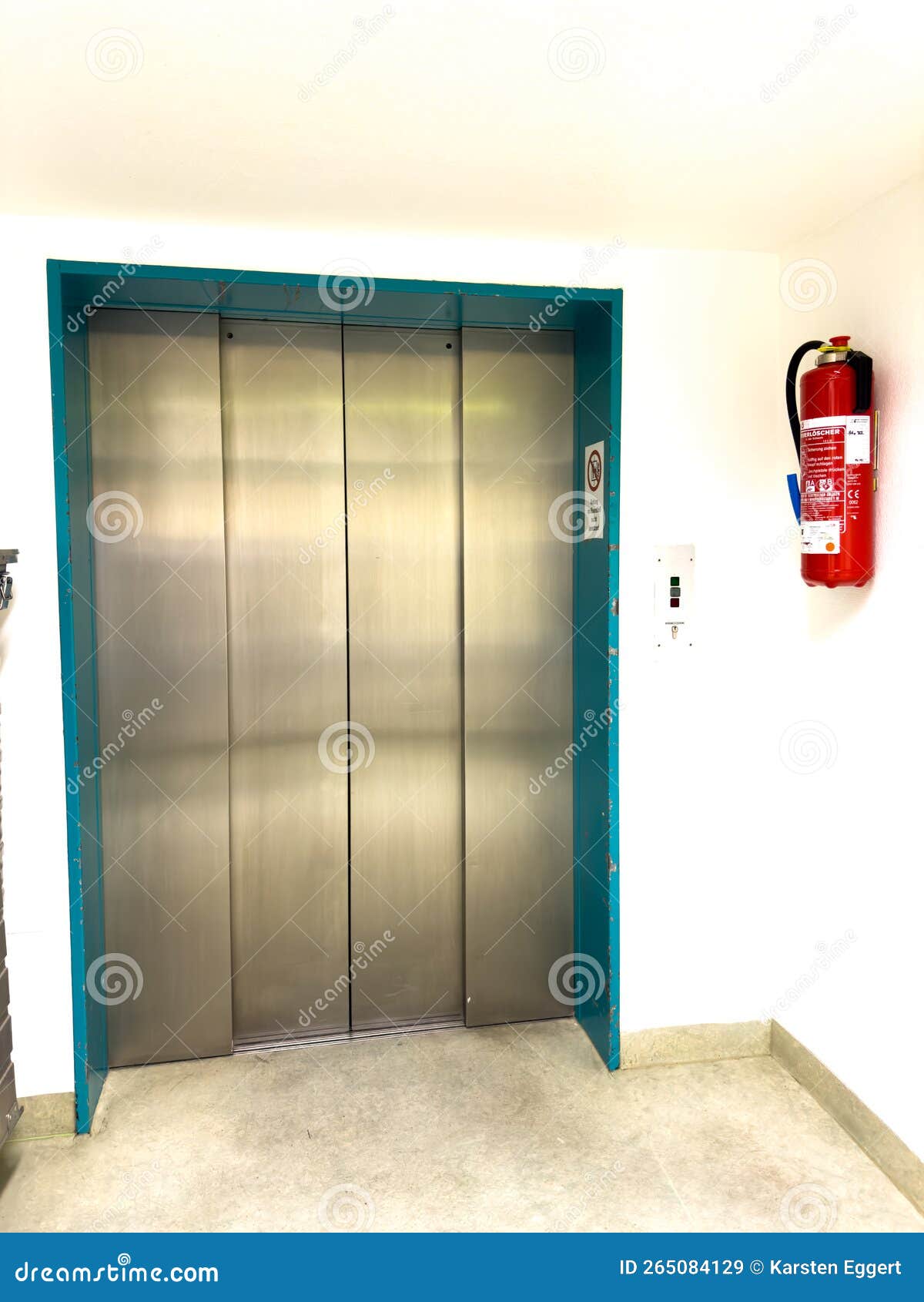 Next To an Elevator Hangs a Large Red Hand Fire Extinguisher Stock ...