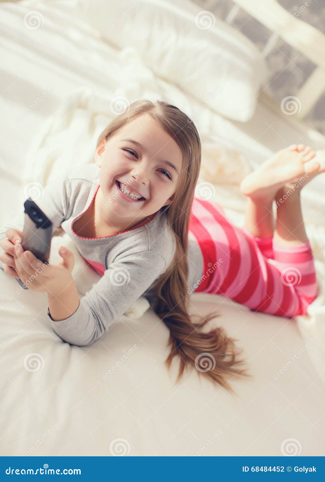 Niña Que Miente En Cama Con Una Tv Teledirigida Foto De Archivo