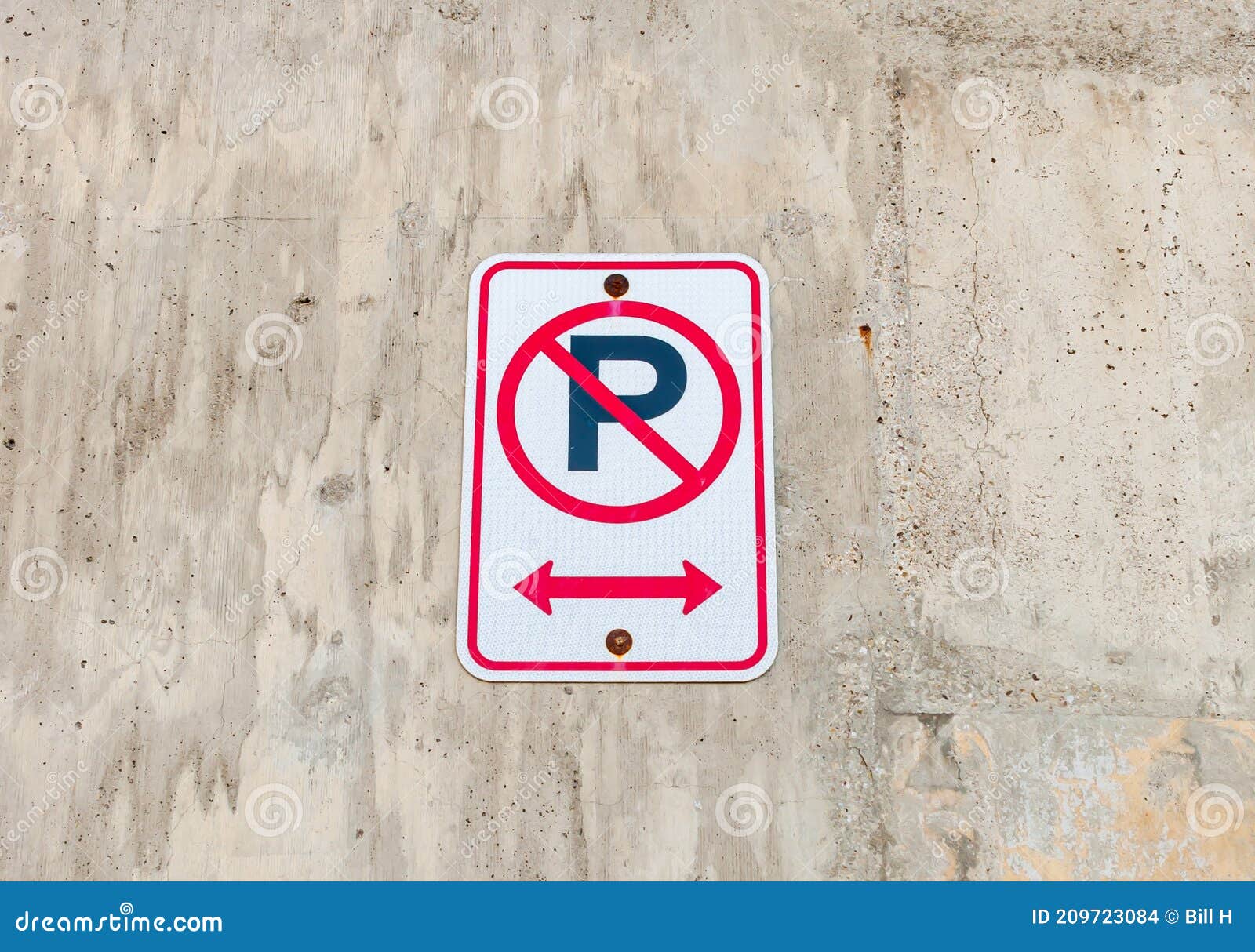 A No Parking Sign on a Textured Concrete Wall with a Directional Arrow ...