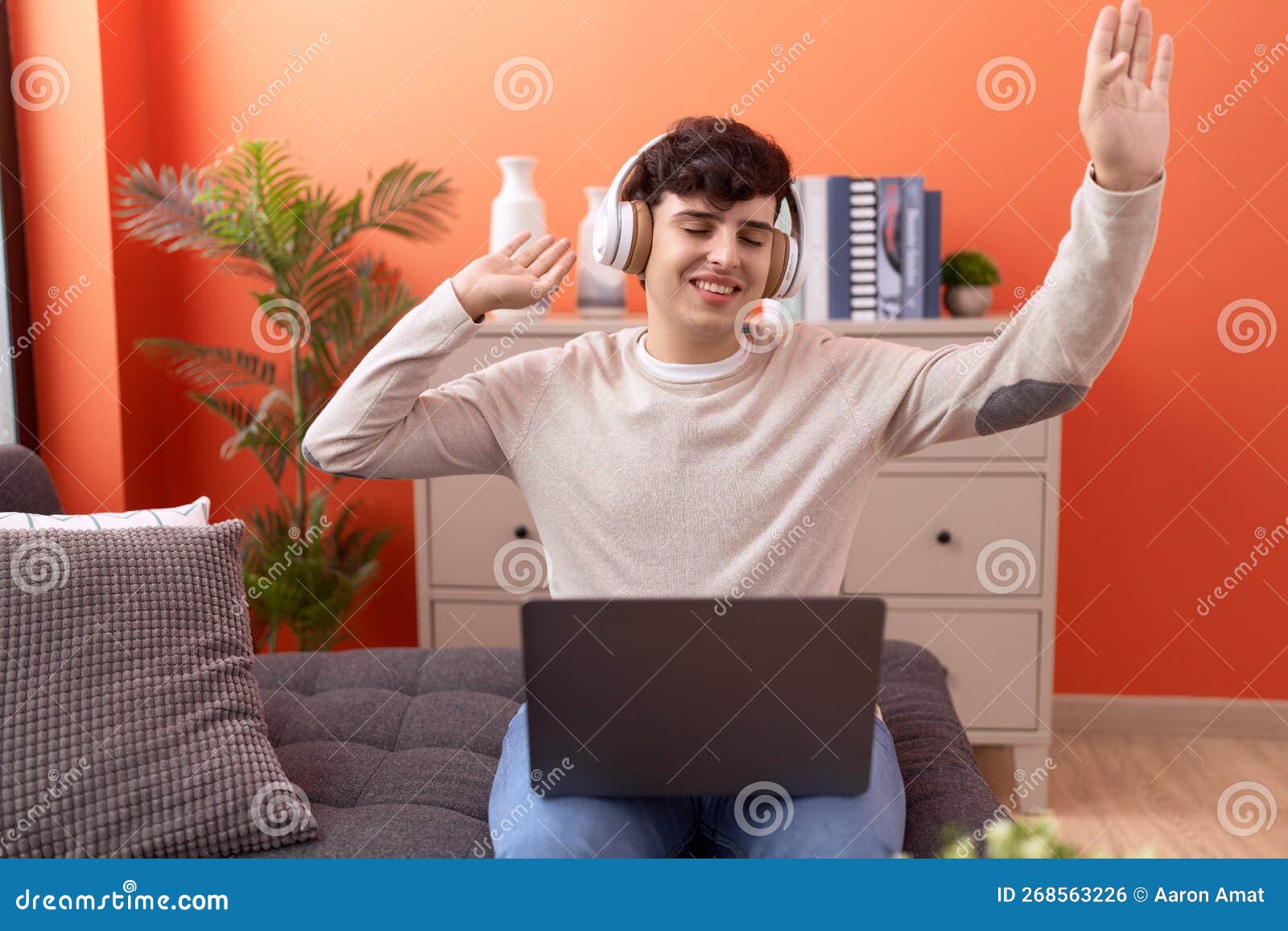 Non Binary Man Dancing and Listening To Music Sitting on Sofa at Home ...