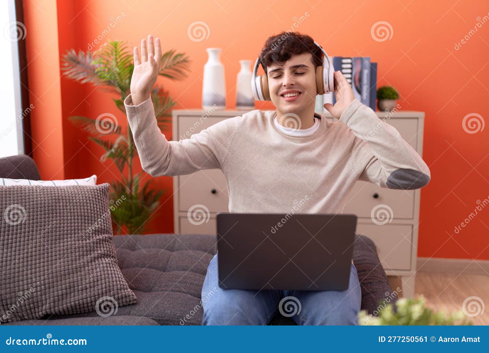 Non Binary Man Dancing and Listening To Music Sitting on Sofa at Home ...