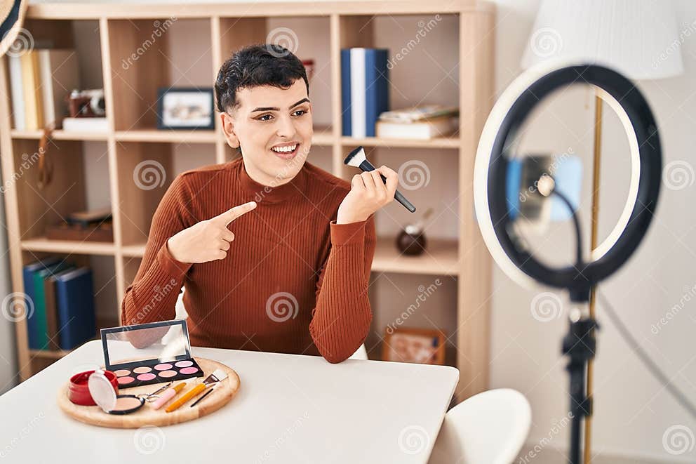 Non Binary Person Recording Vlog Tutorial with Smartphone at Home Smiling Happy Pointing with ...