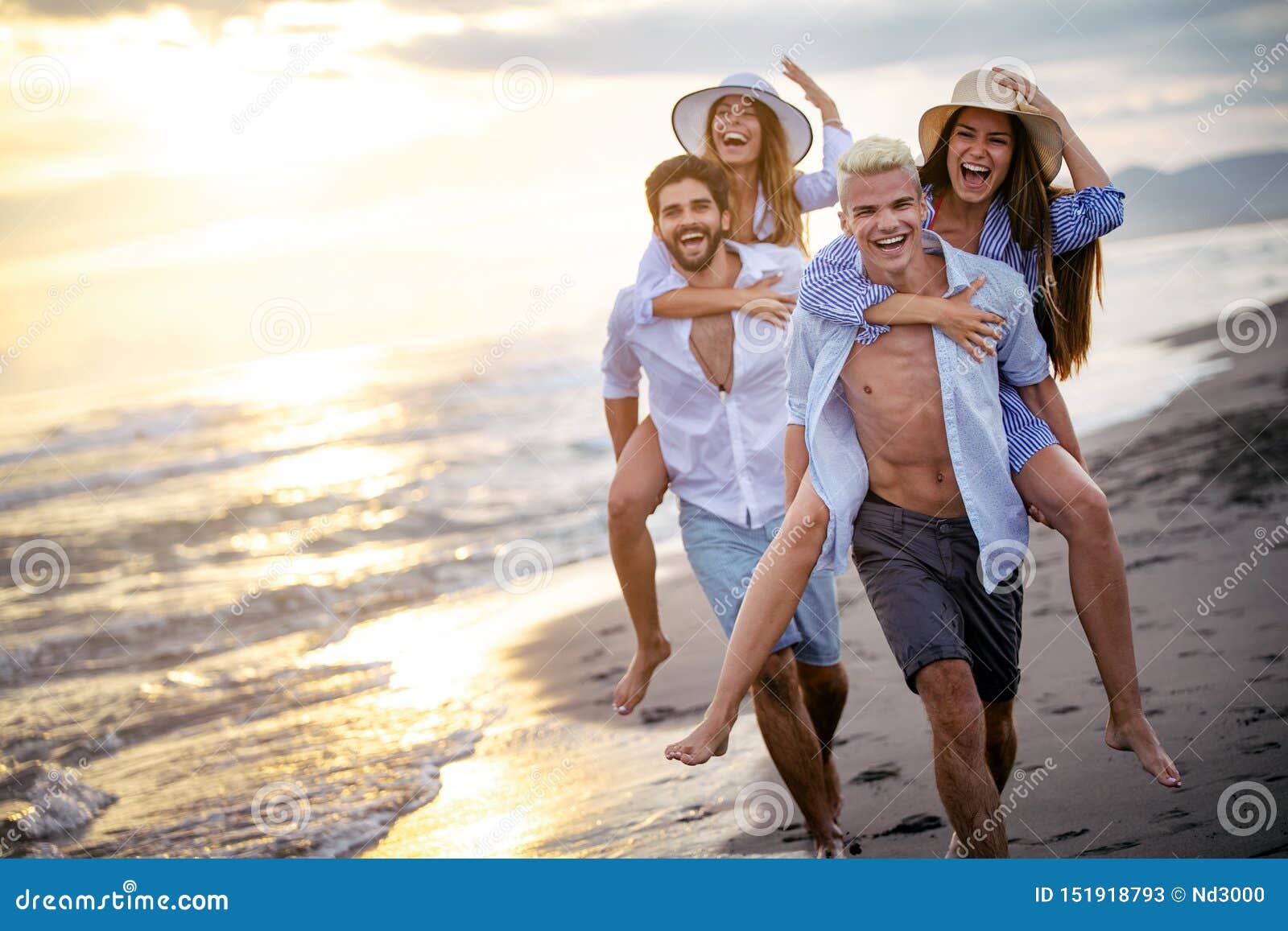 Novios Felices Que Llevan A Cuestas A Sus Novias En La Playa Imagen De Archivo Imagen De