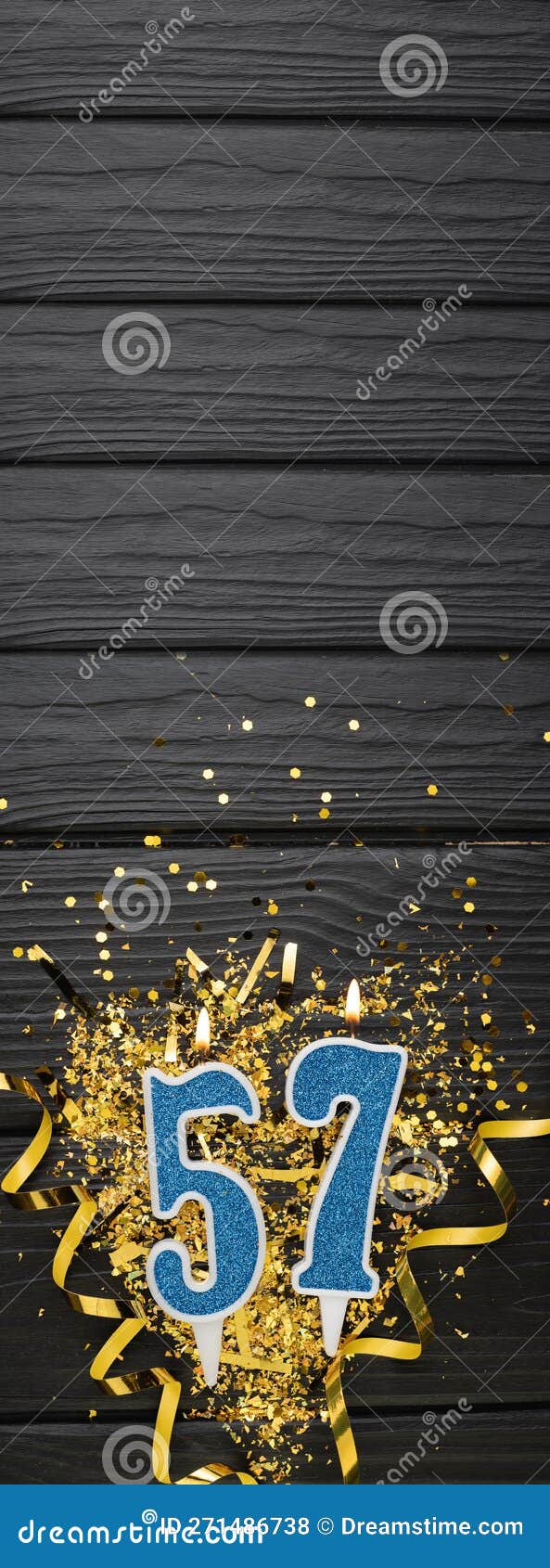 Number 57 Blue Celebration Candle And Gold Confetti On Dark Wooden