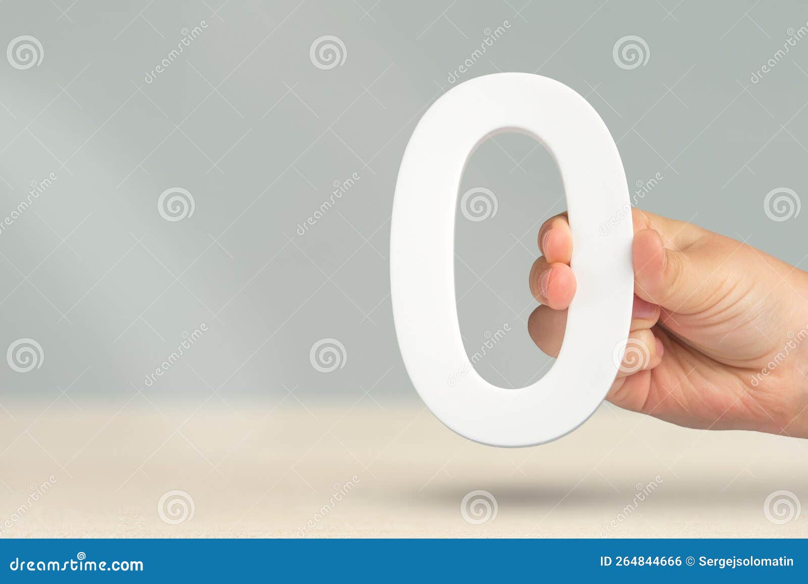 Numeral Zero in Hand. a Hand Holds a White Number Zero on a Blurred ...