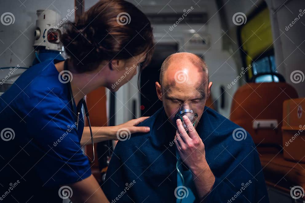 Nurse Puts Her Hand On Man Who Sits In Oxygen Mask In Blanket In The