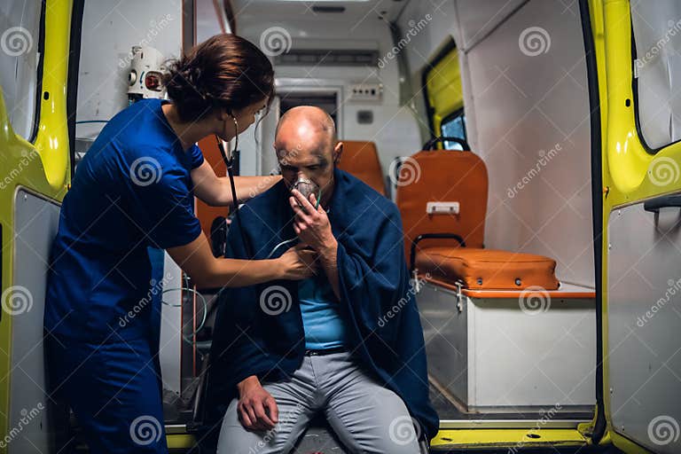 Nurse With Stethoscope And Man Sits In Oxygen Mask In Blanket In The
