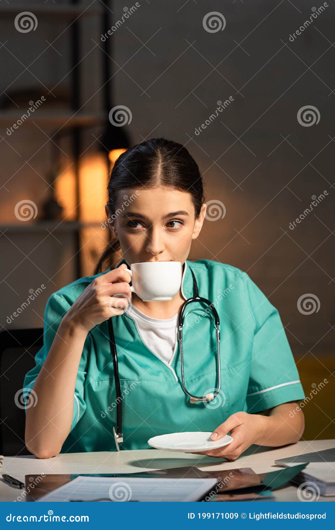 Nurse in Uniform Sitting at Table and Drinking Coffee during Night ...