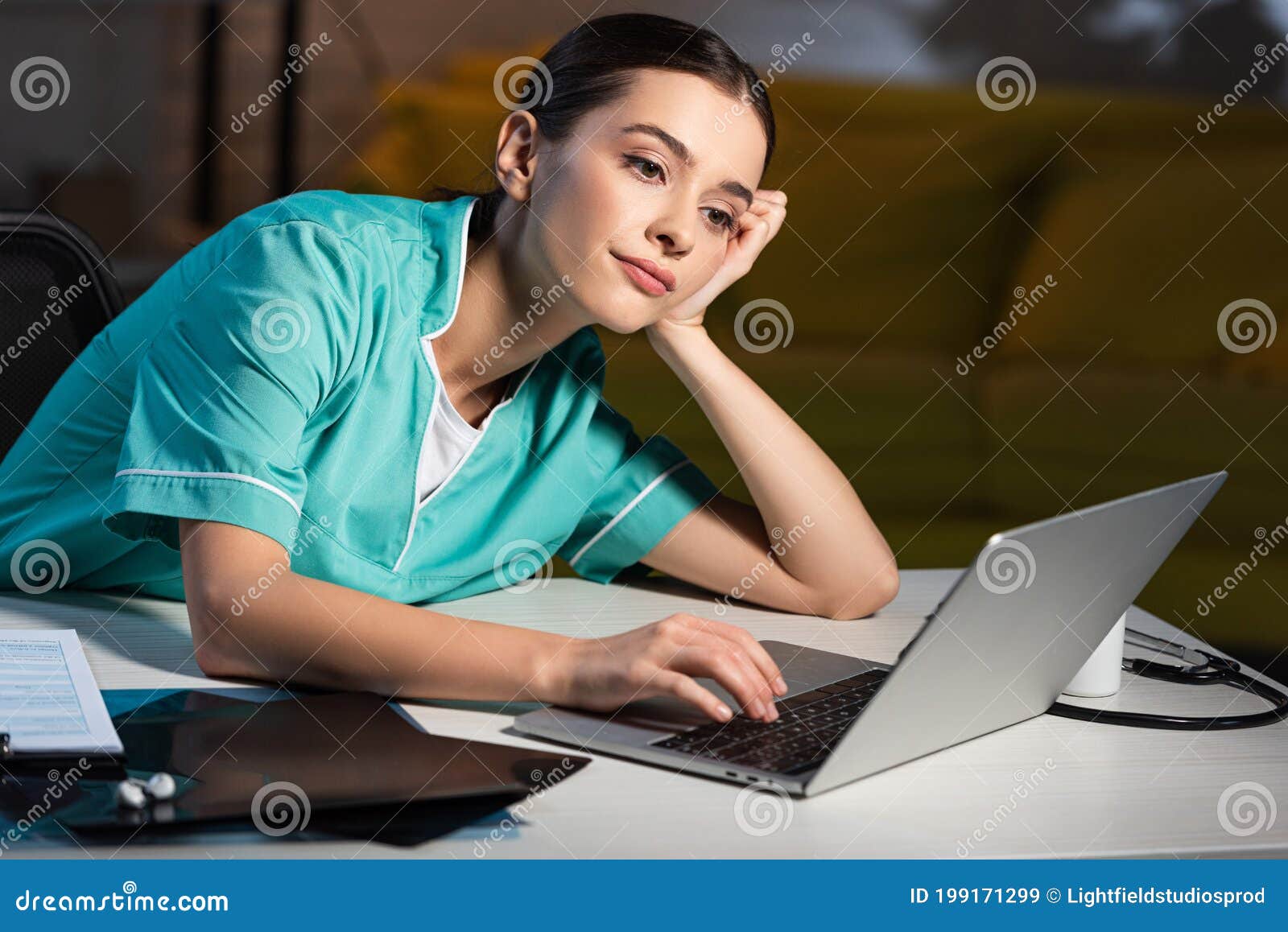 Nurse in Uniform Sitting at Table and Using Laptop during Night Shift ...
