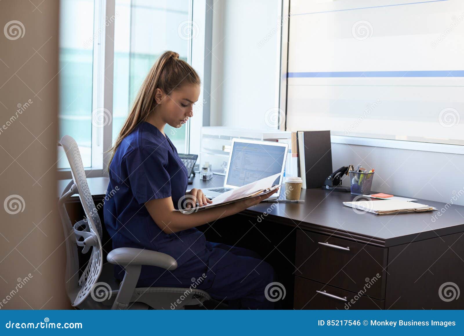 Nurse Wearing Scrubs Working at Desk in Office Stock Photo - Image of ...
