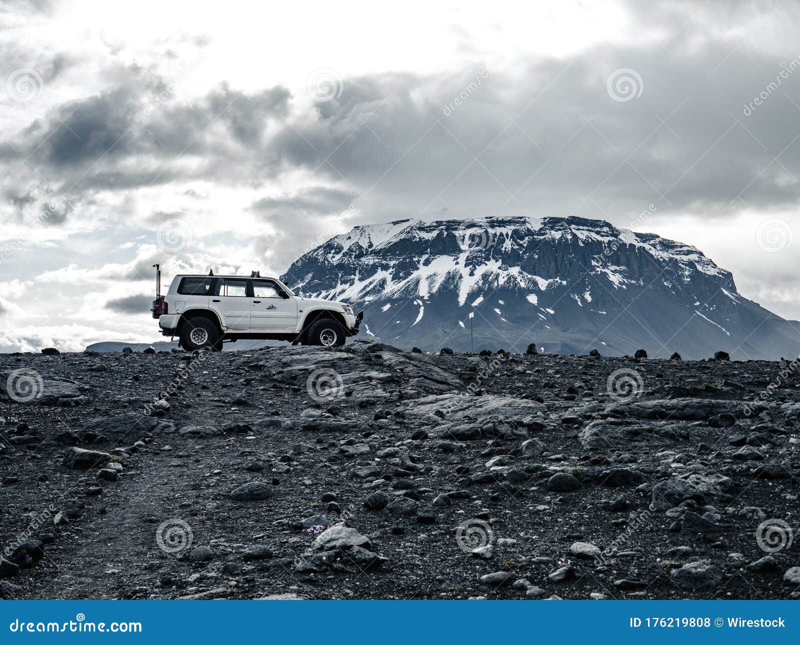 Off Road White SUV on a Bumpy Ground in Front of a Snowy Mountain Stock ...
