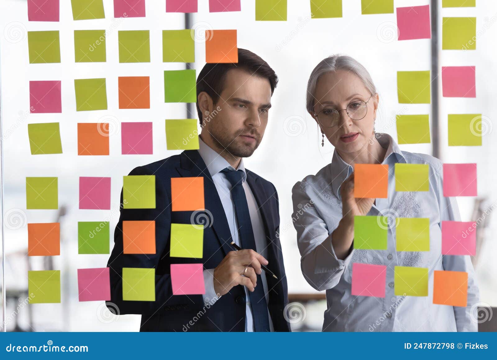 Office Employees Writing on Sticky Notes Attached on Wall Stock Photo ...