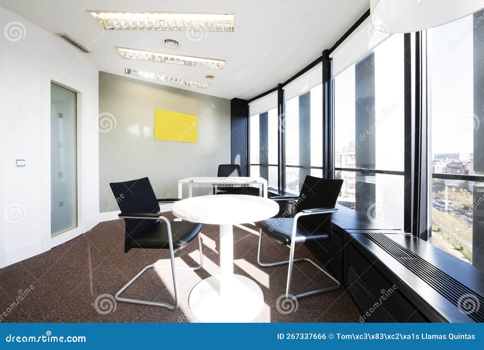 Office with a Small White Round Table Next To a Large Window with a ...