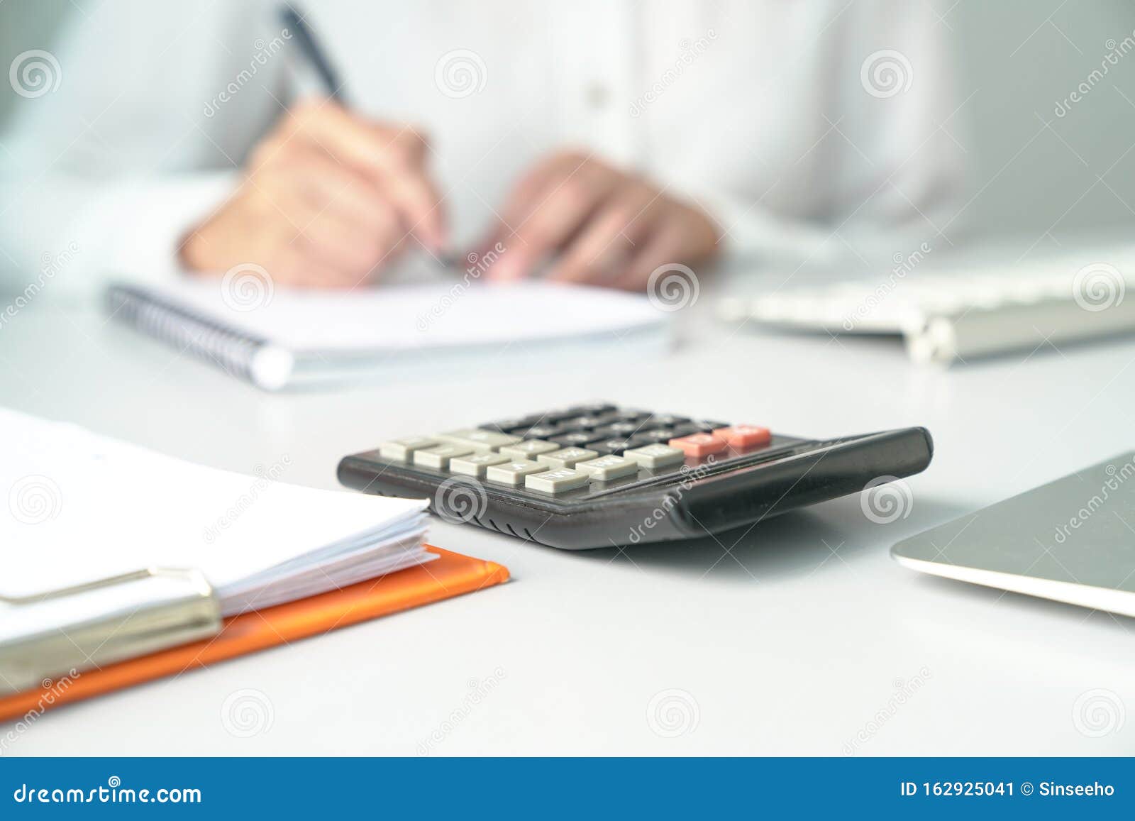 Office Table View with Out of Focus on Accountant, Focus on Calculator ...