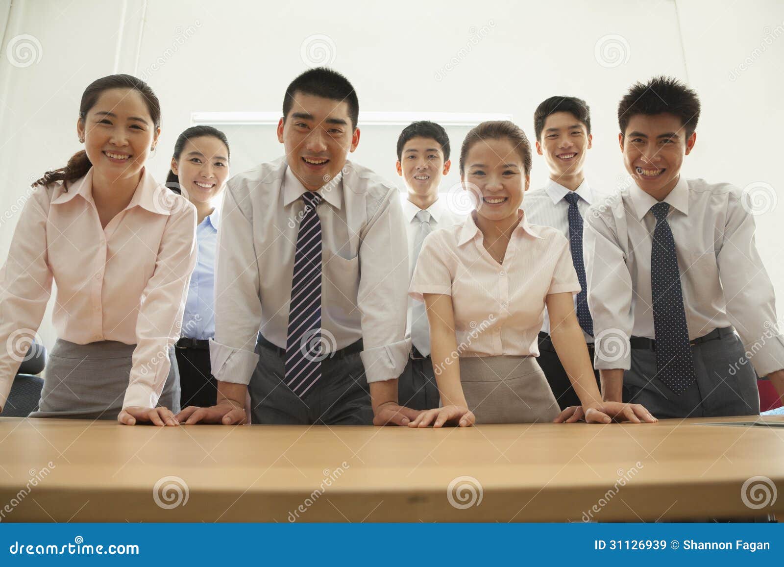Office Team Leaning Over the Table and Looking at Camera, Portrait ...