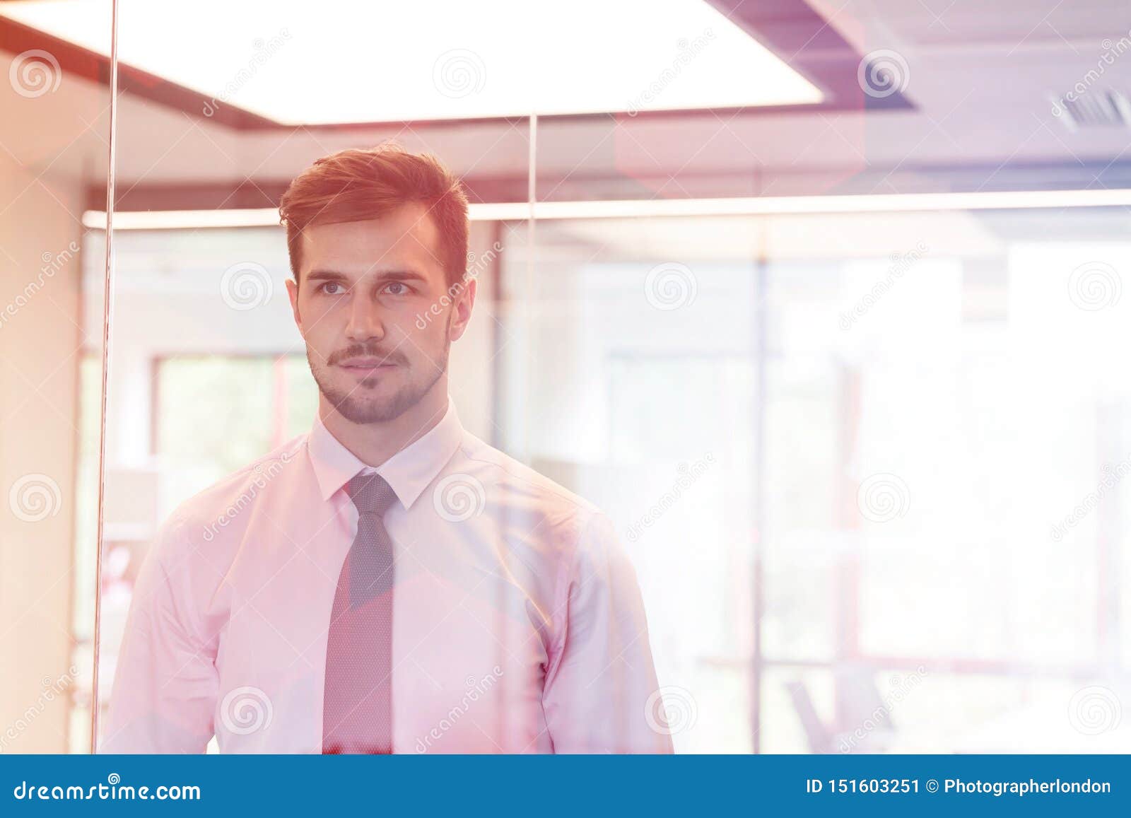 Thoughtful Young Professional Looking through Glass Window at Office ...