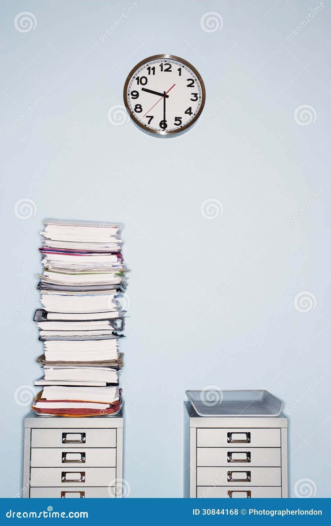 Office Wall with Clock Stack of Paperwork in Inbox on File Cabinet ...