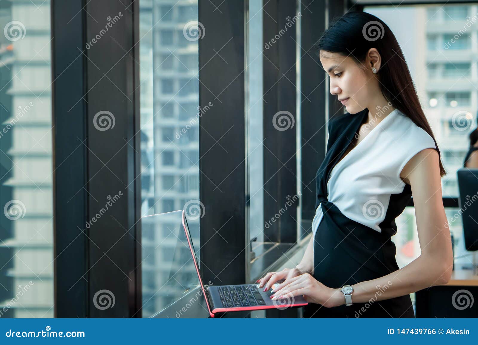 Office Woman Standing Near Window And Using Laptop Computer In Office