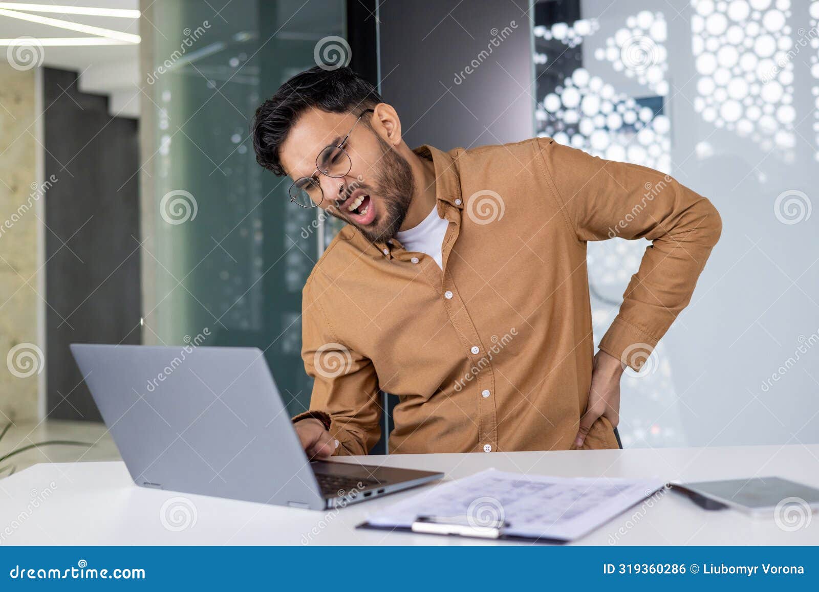Office Worker Suffering from Back Pain while Working on a Laptop Stock ...